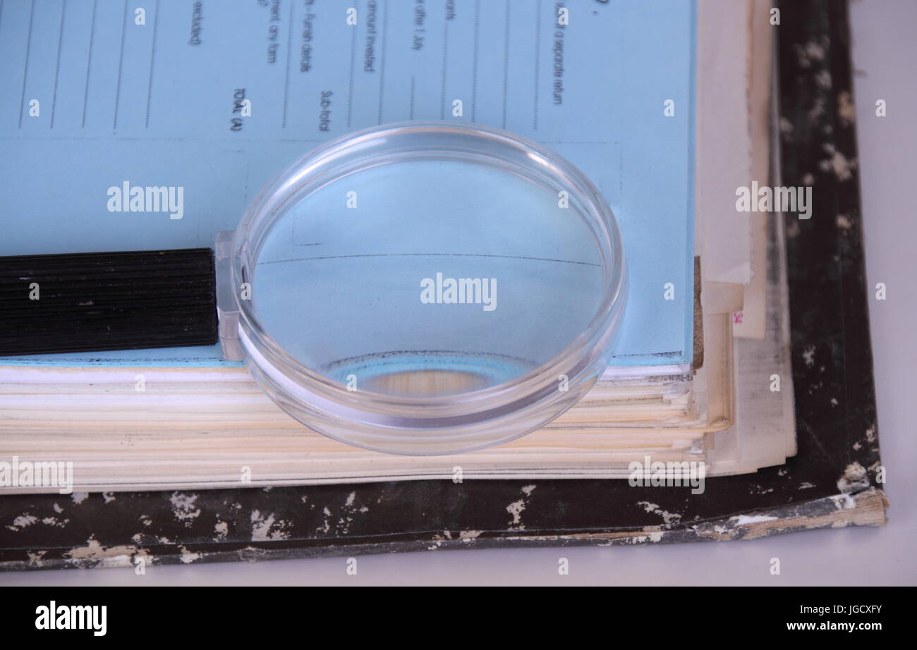 A paper file with documents and a magnifying glass on a white ...