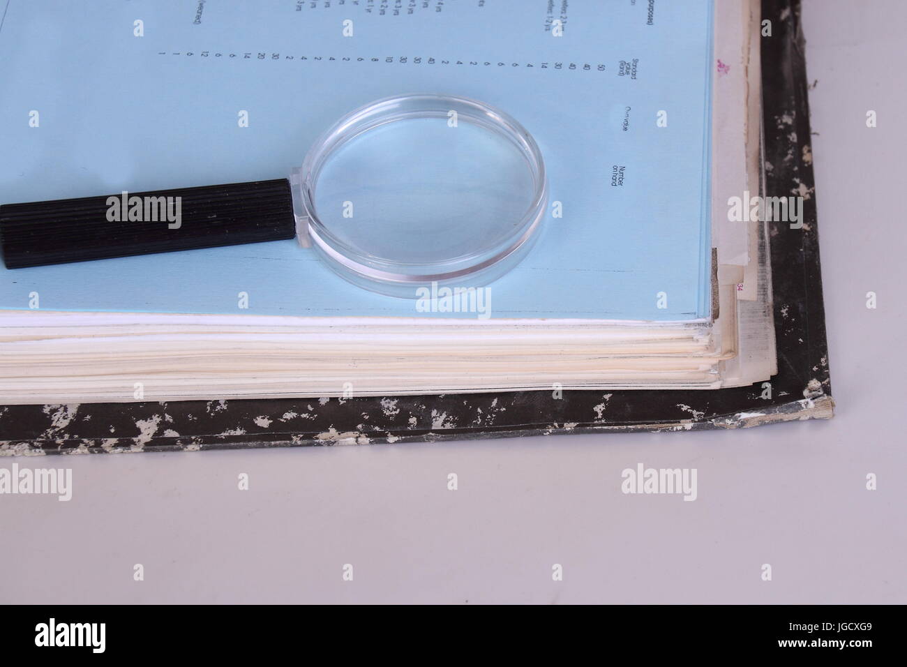 A paper file with documents and a magnifying glass on a white ...