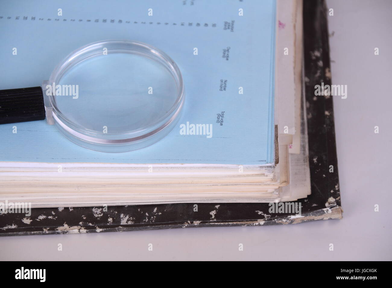 A paper file with documents and a magnifying glass on a white ...