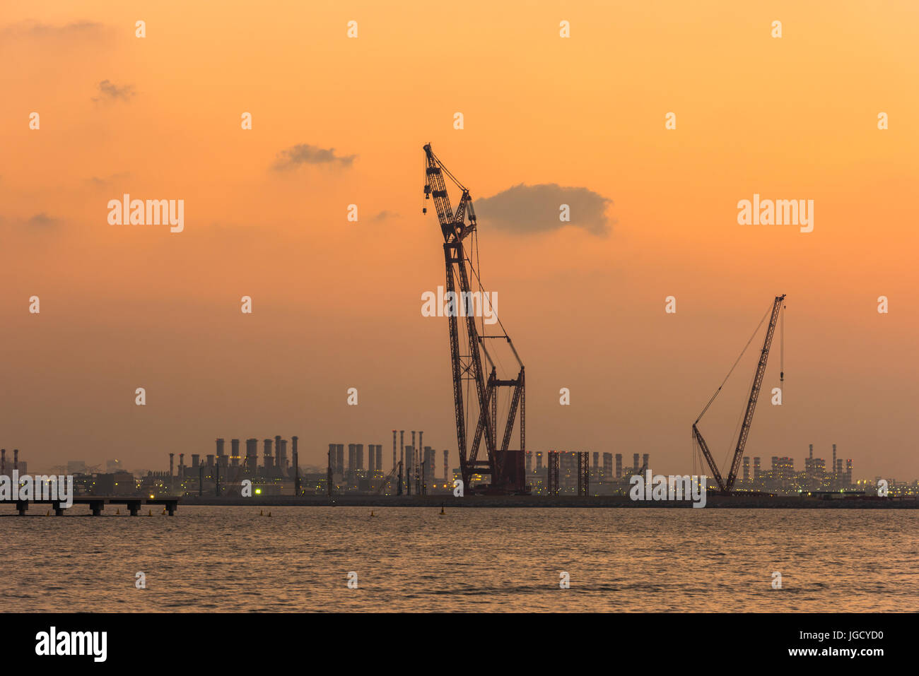 Sunset at the Dubai seaport, UAE. Silhouette of cranes on a bright sky ...