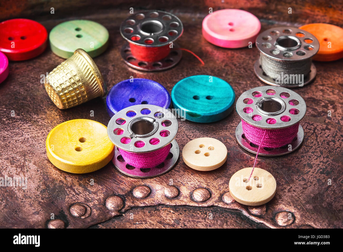 plastic sewing button and thread coil on a copper retro background ...