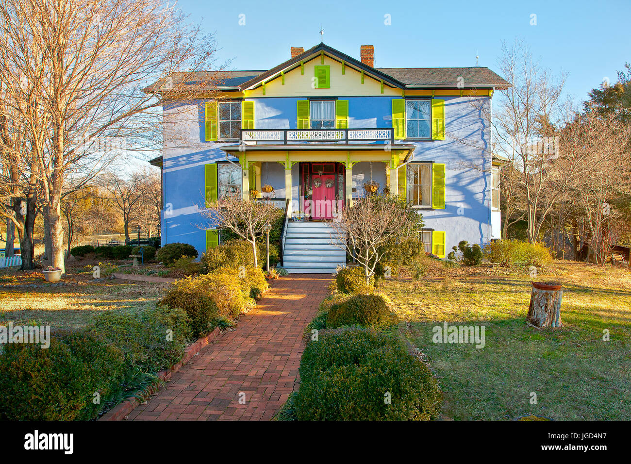 Colorful Victorian house, brick walkway, bare trees in yard, pink door ...