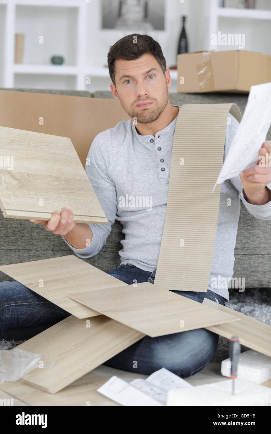 frustrated man reading instruction and putting together self assembly ...