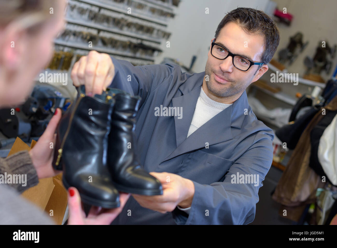 shoemaker giving shoes back to customer Stock Photo - Alamy