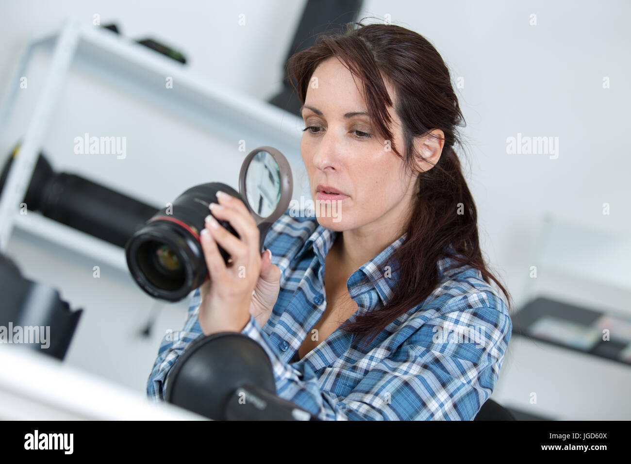woman checking camera lense using a magnifying glass Stock Photo - Alamy