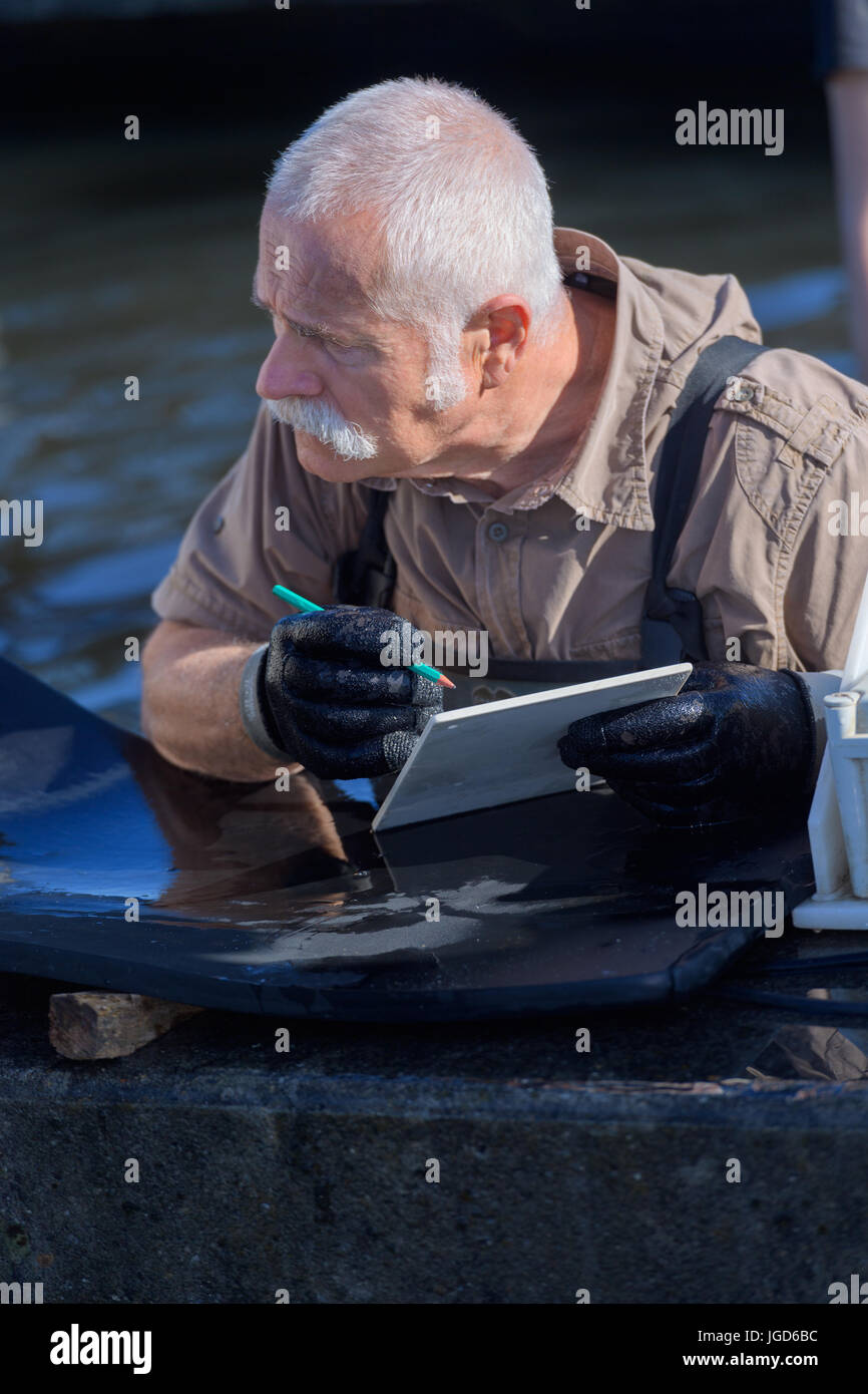 senior fish farm manager writing on clipboard Stock Photo - Alamy