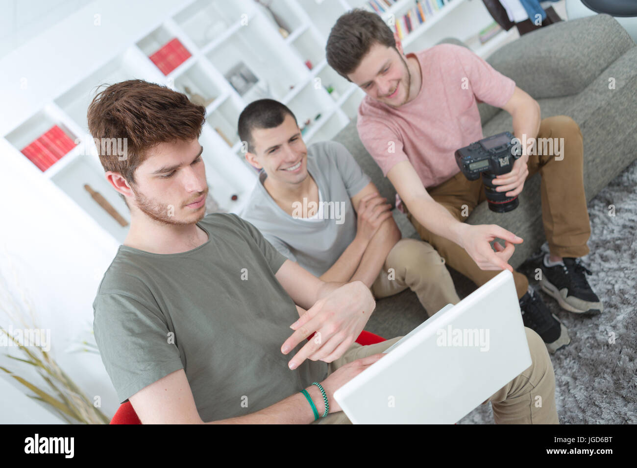 three friends together reviewing photos of their shooting Stock Photo ...