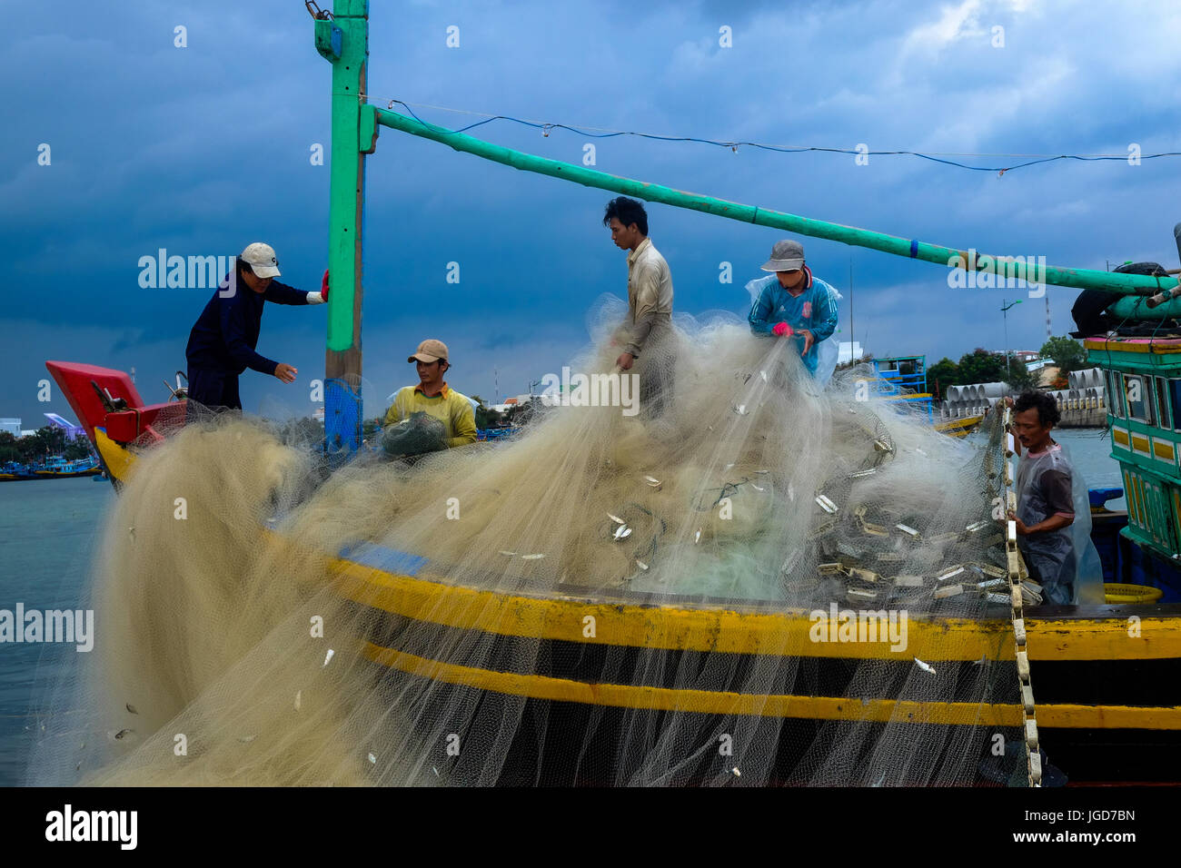 Vietnamese fishermen cast nets from their boat at Phan Thiet, Vietnam ...