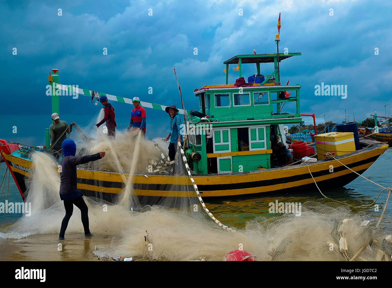 Vietnamese fishermen cast nets from their boat at Phan Thiet, Vietnam ...