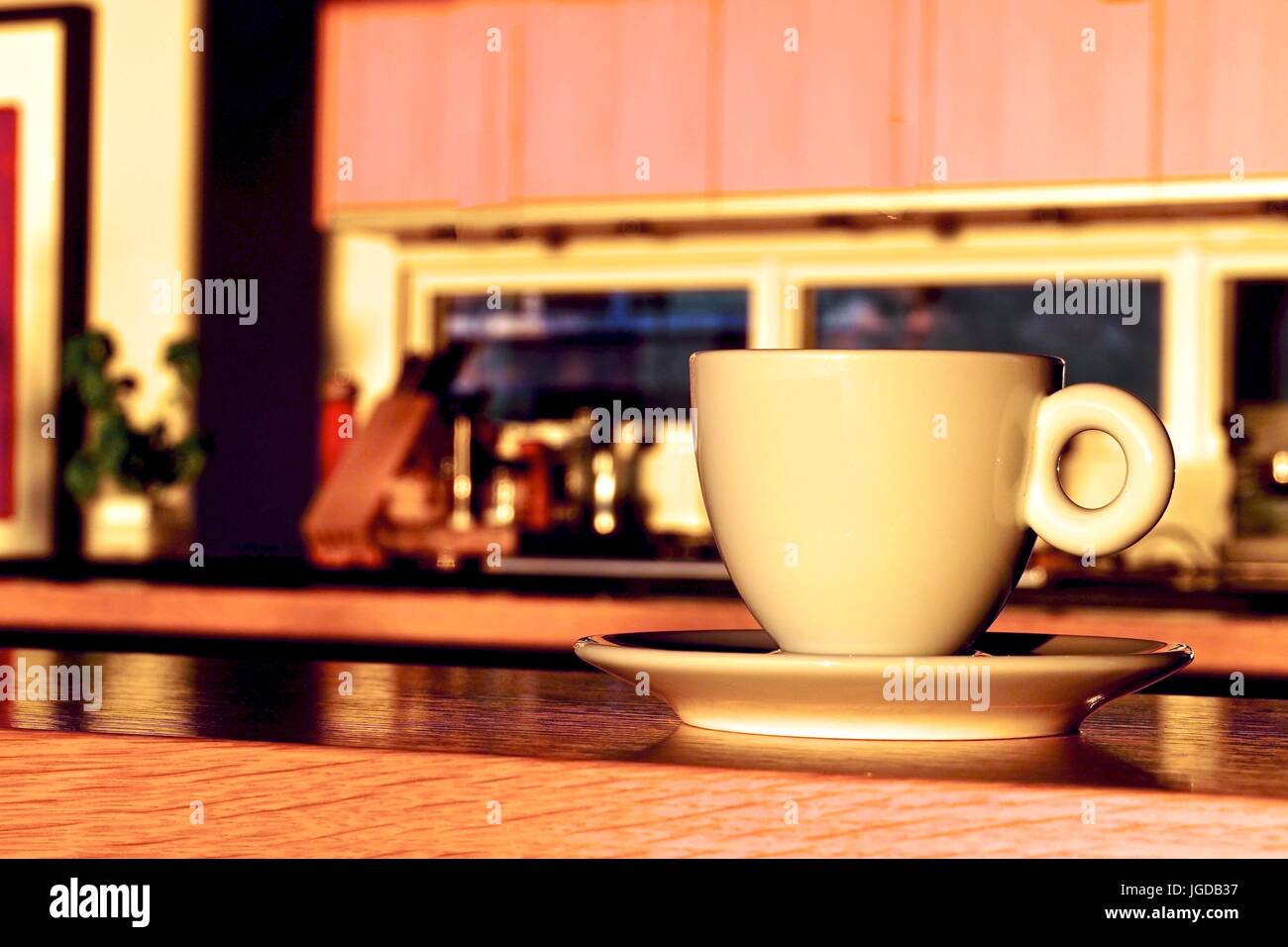 Close up of a coffee cup and saucer in front of kitchen scene Stock ...