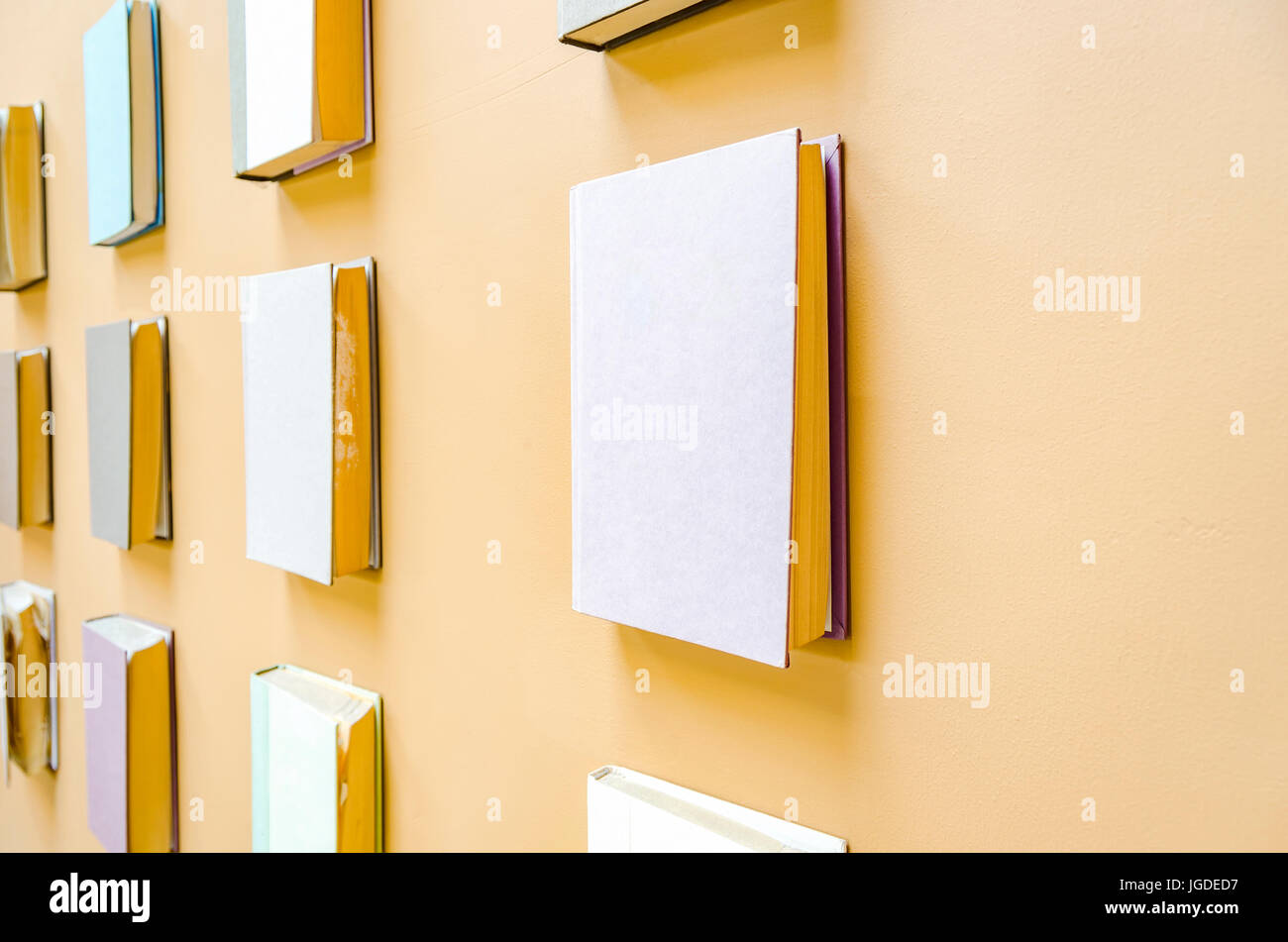 Real books stuck onto wall as a decorative design Stock Photo - Alamy