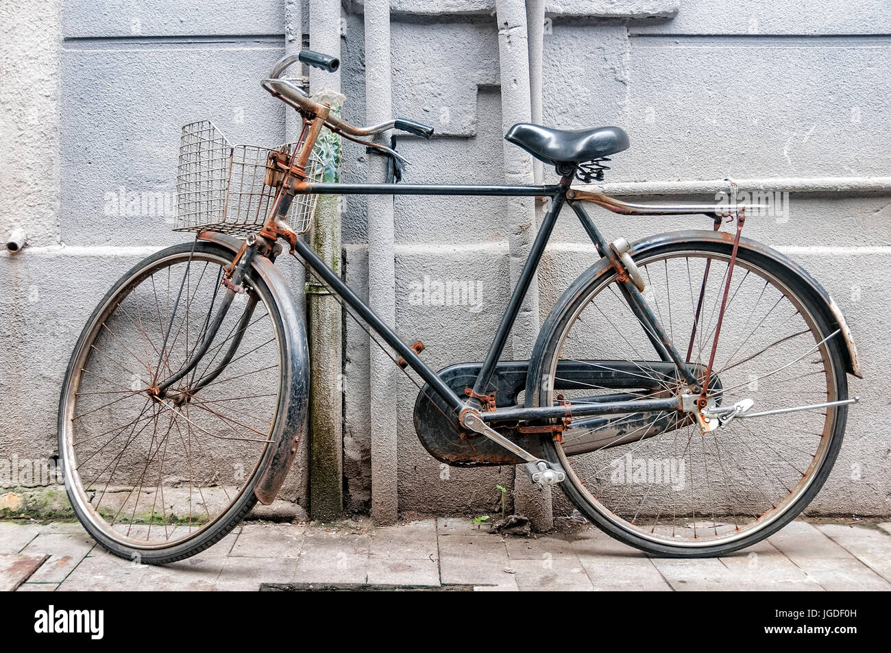 Old and rusty bicycle parked against a gray city wall Stock Photo - Alamy