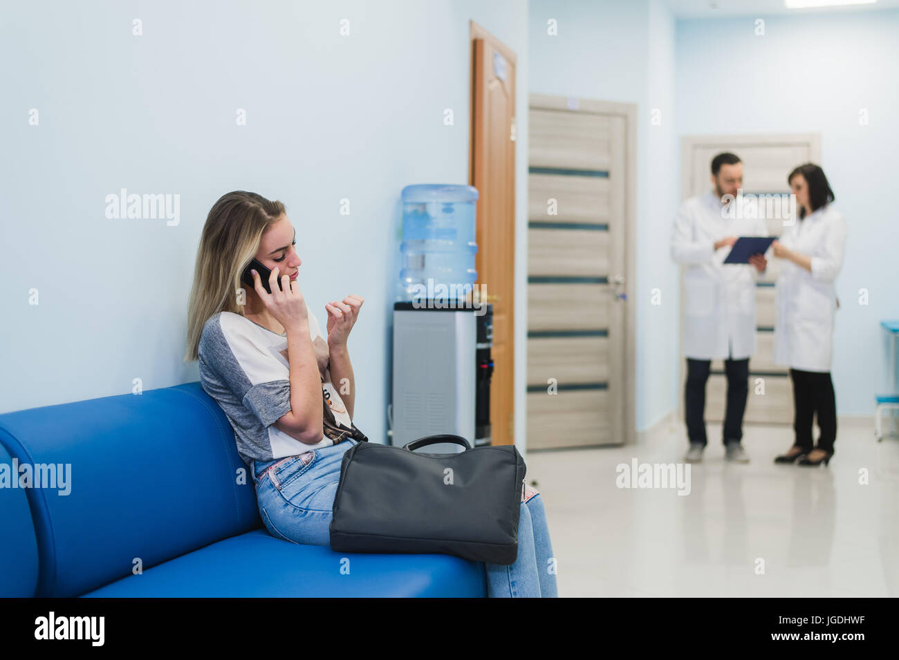 Woman patient in speaking at the mobile phone in hospital waiting room ...