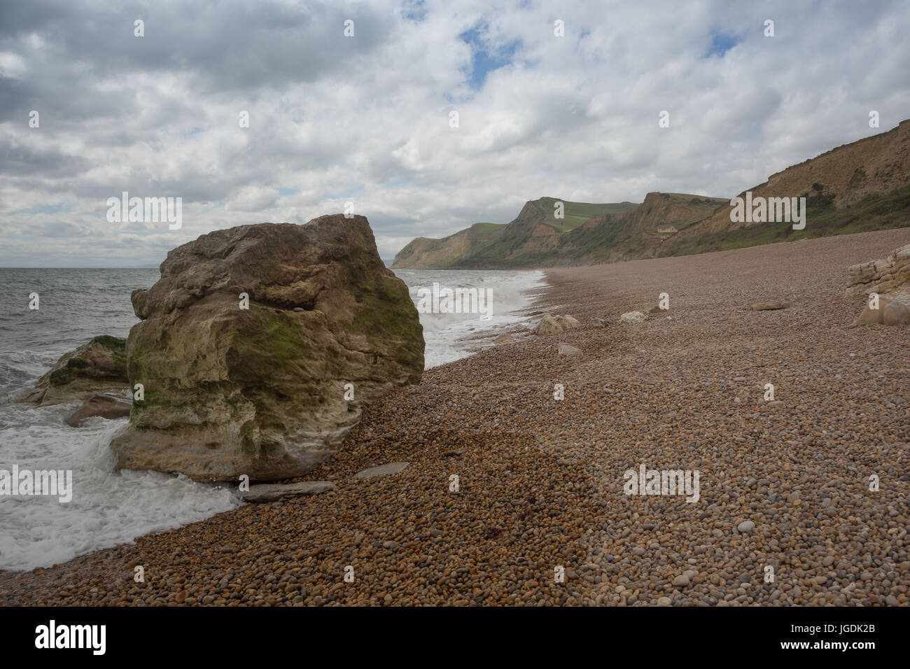 Costal seaside view with large rock in foreground on a cloudy day ...