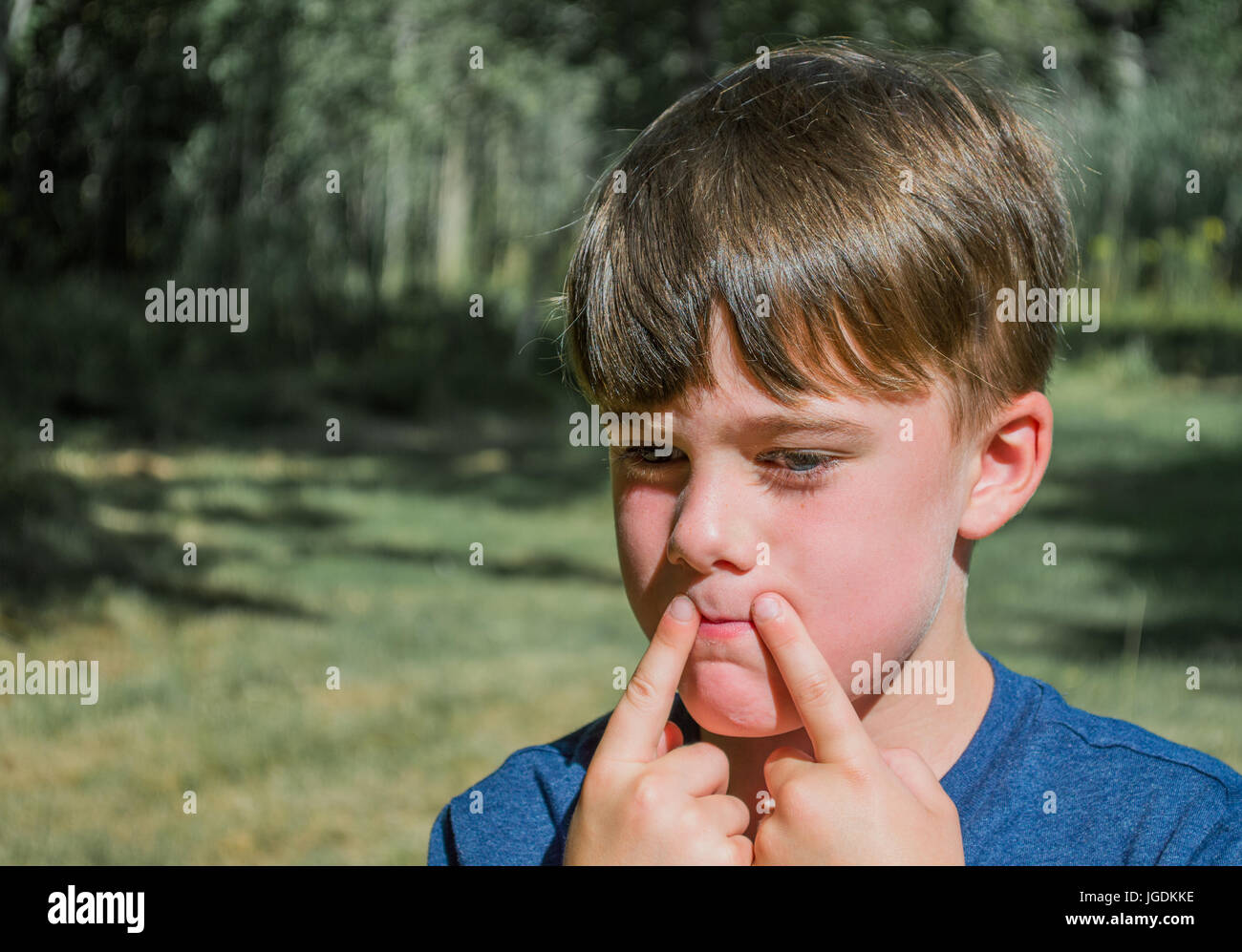 young caucasian boy outdoors poking his face with his fingers Stock ...