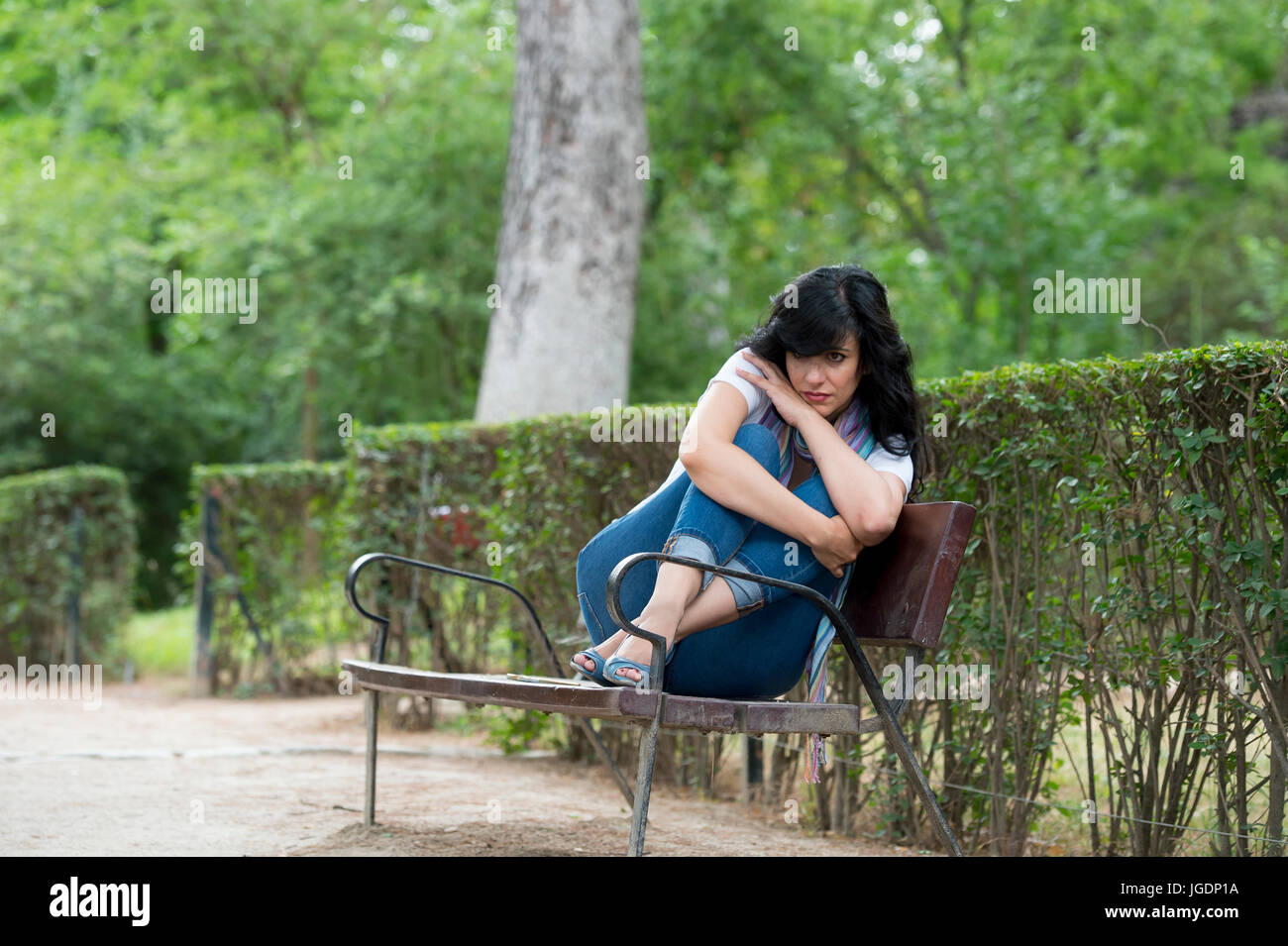 attractive beautiful latin woman sitting on a park bench feeling sad ...