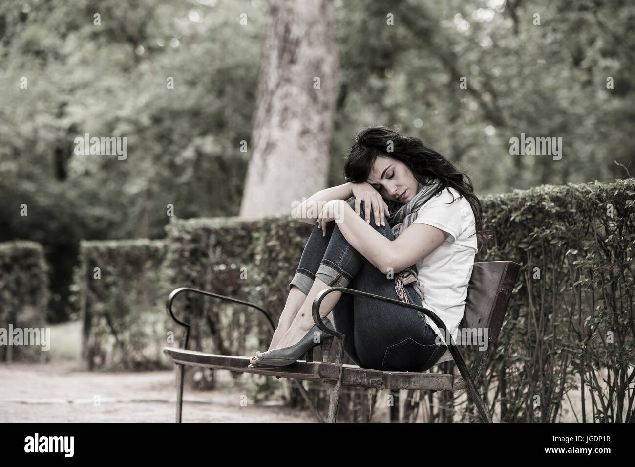 attractive beautiful latin woman sitting on a park bench feeling sad ...