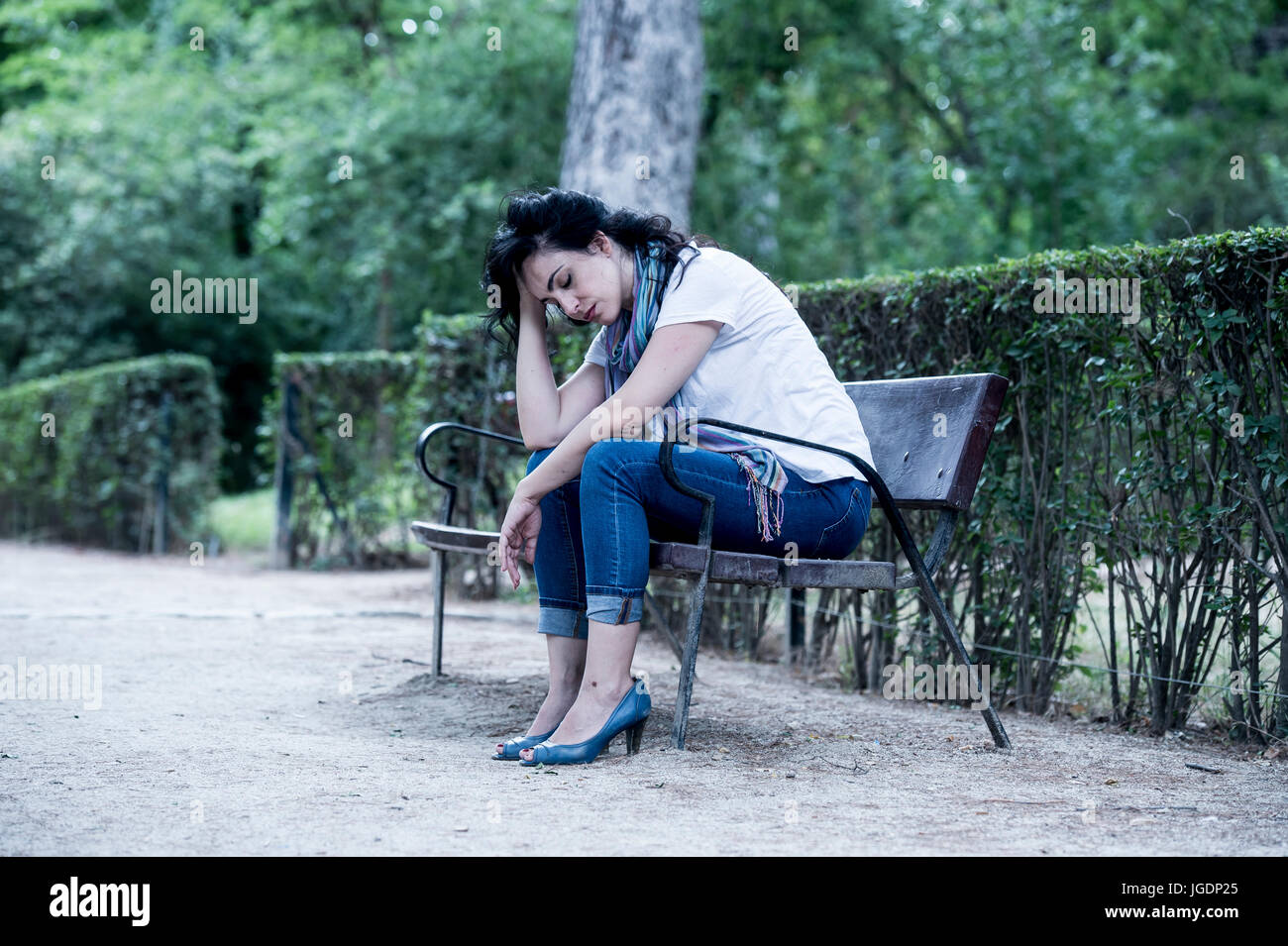 attractive beautiful latin woman sitting on a park bench feeling sad ...