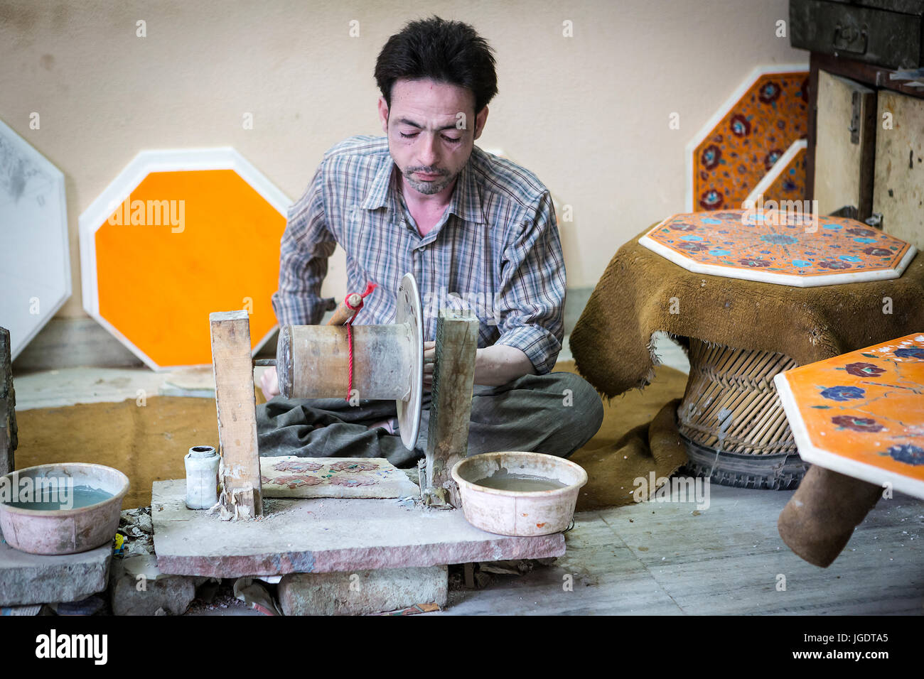 Pale skinned man in India shaping pieces of marble and semi-precious ...