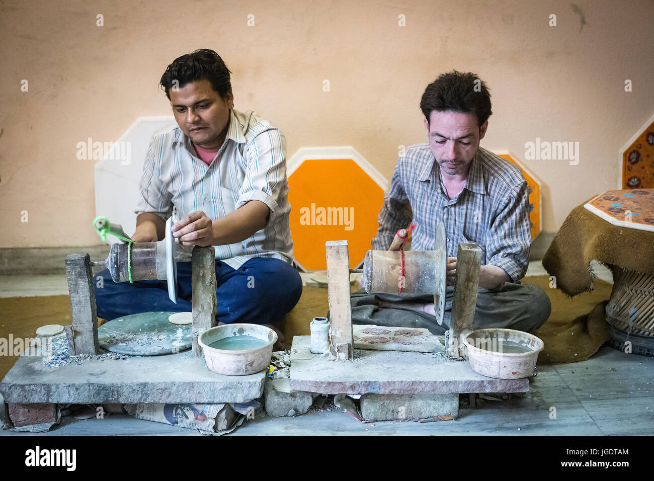 Pale skinned man and darker skinned man in India shaping pieces of ...