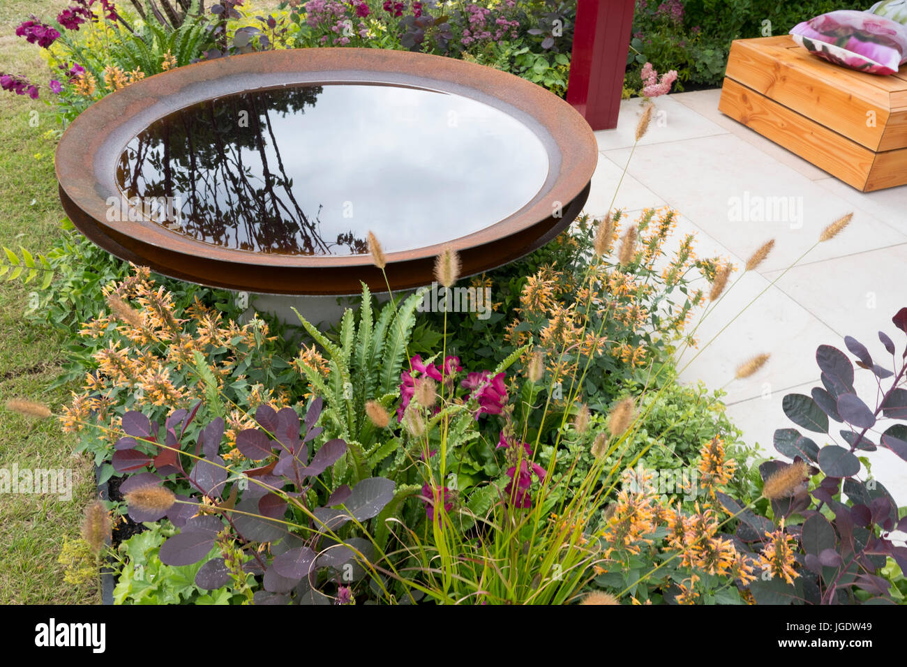 A water filled metal cauldron surrounded by plants including Agastache ...