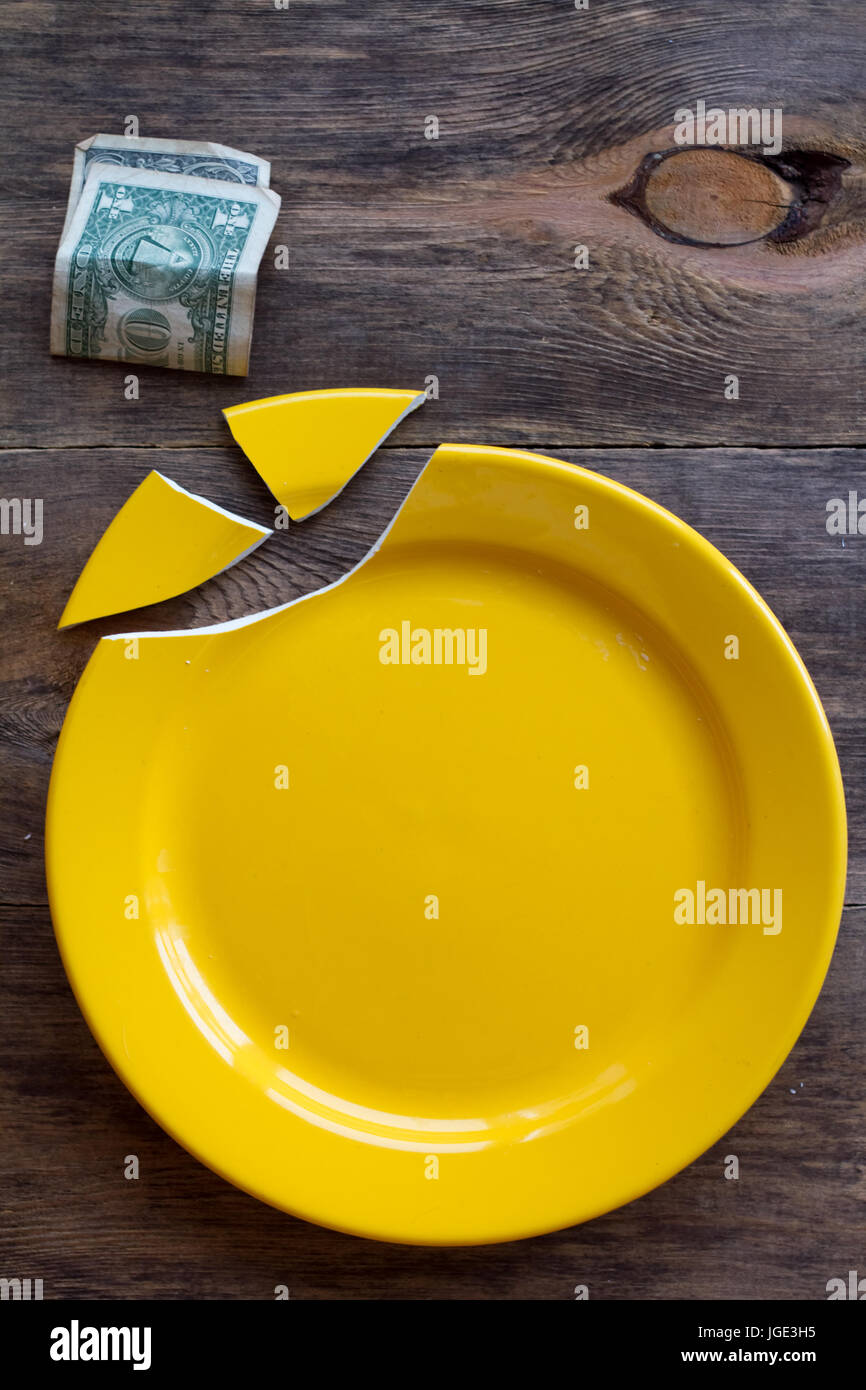 Broken plate yellow and one dollar old paper on wooden background Stock ...