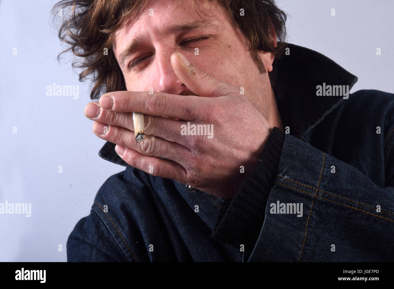 Portrait of a man smoking tobacco and coughing on white background ...