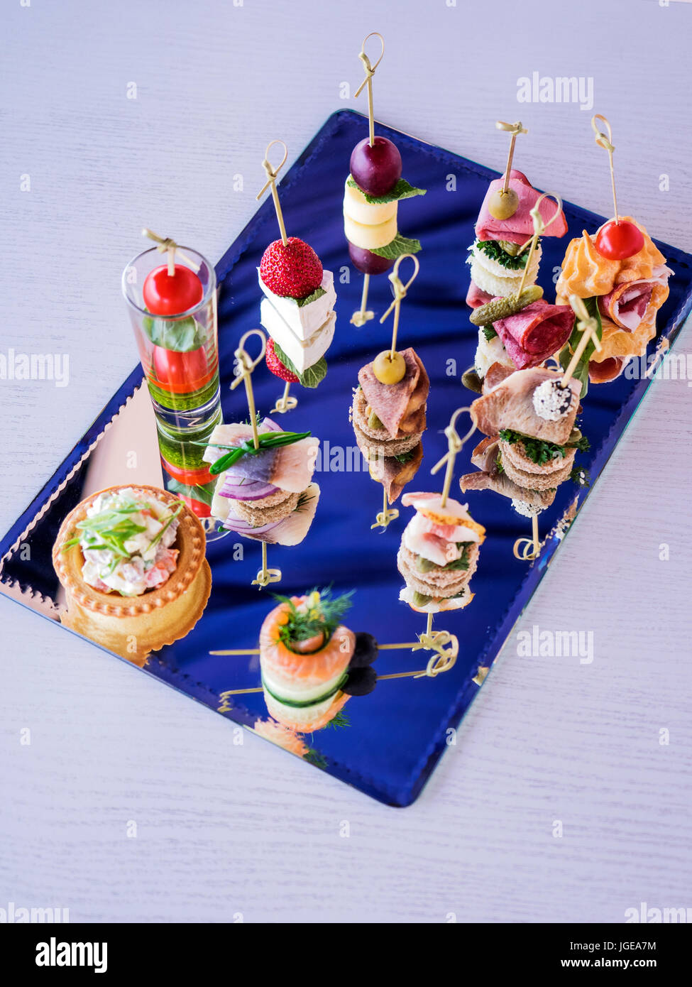 Set of different canapes and snacks served on a platter with a mirror ...