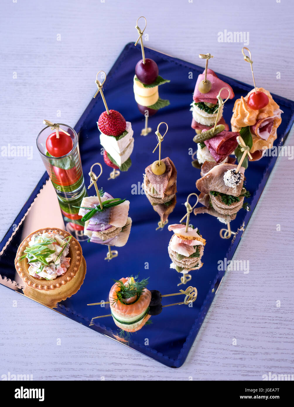 Set of different canapes and snacks served on a platter with a mirror ...