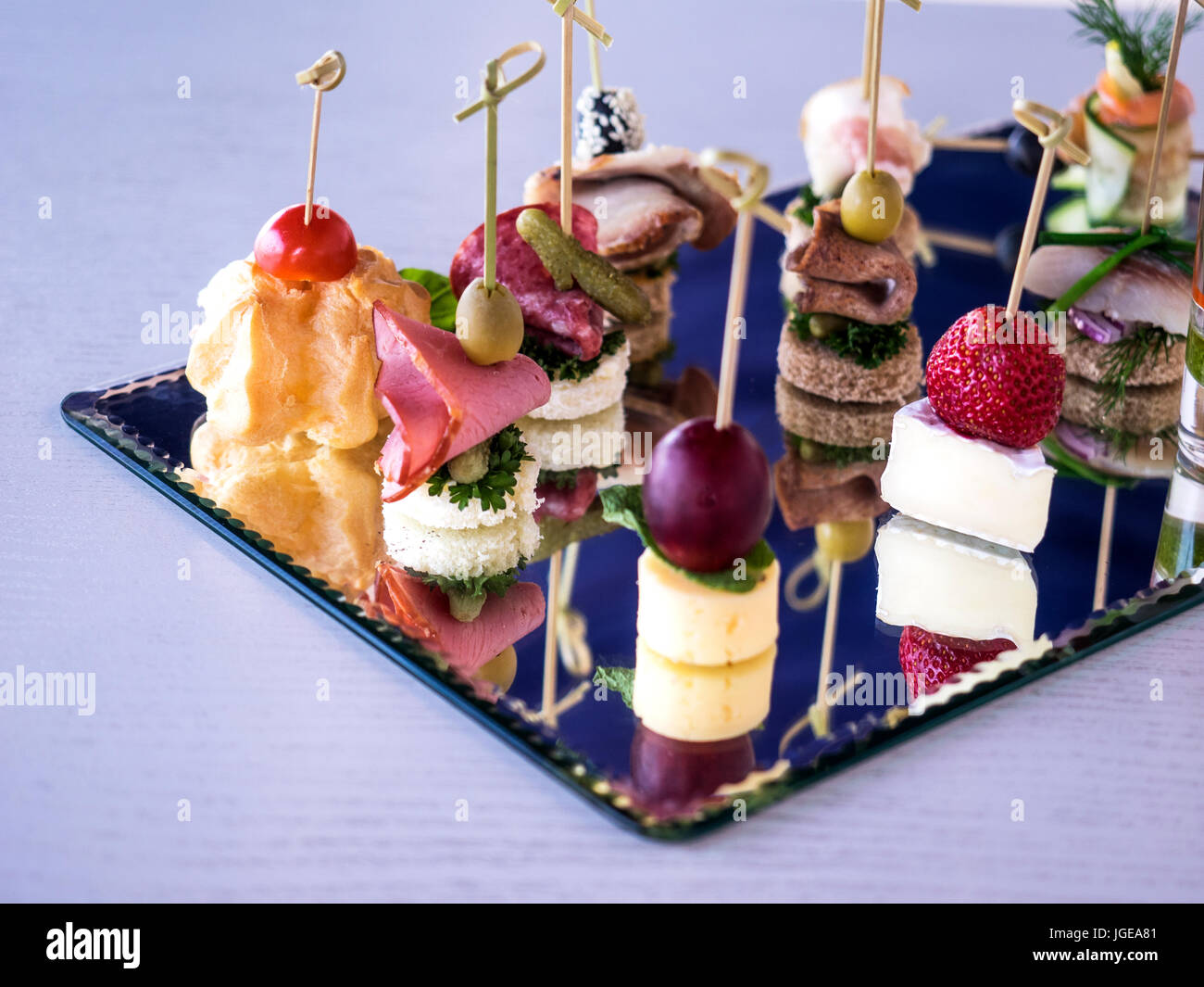 Set of different canapes and snacks served on a platter with a mirror ...