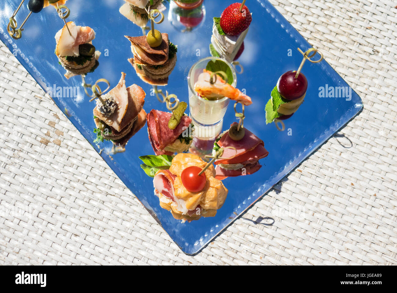 Set of different canapes and snacks served on a platter with a mirror ...