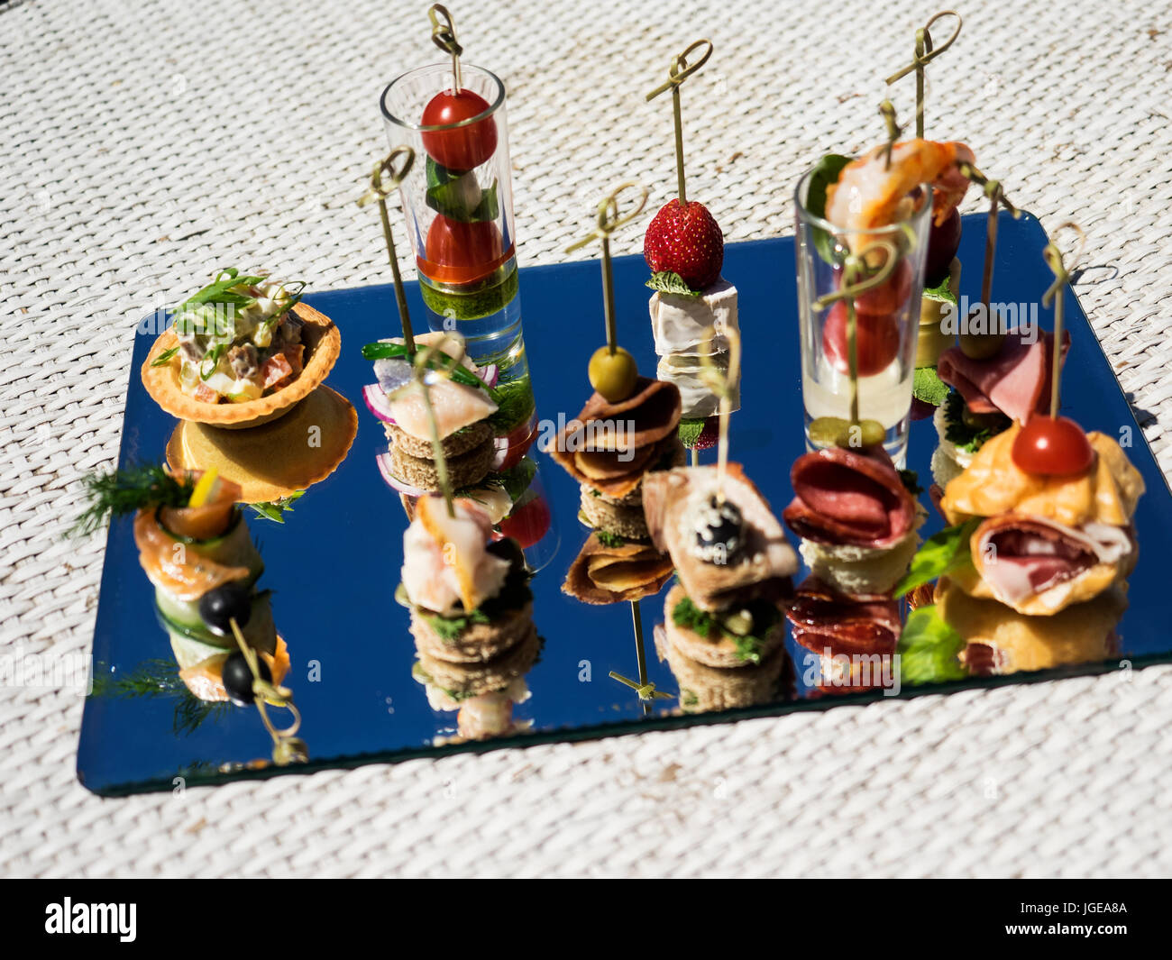 Set of different canapes and snacks served on a platter with a mirror ...