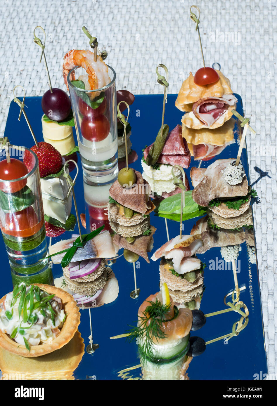 Set of different canapes and snacks served on a platter with a mirror ...