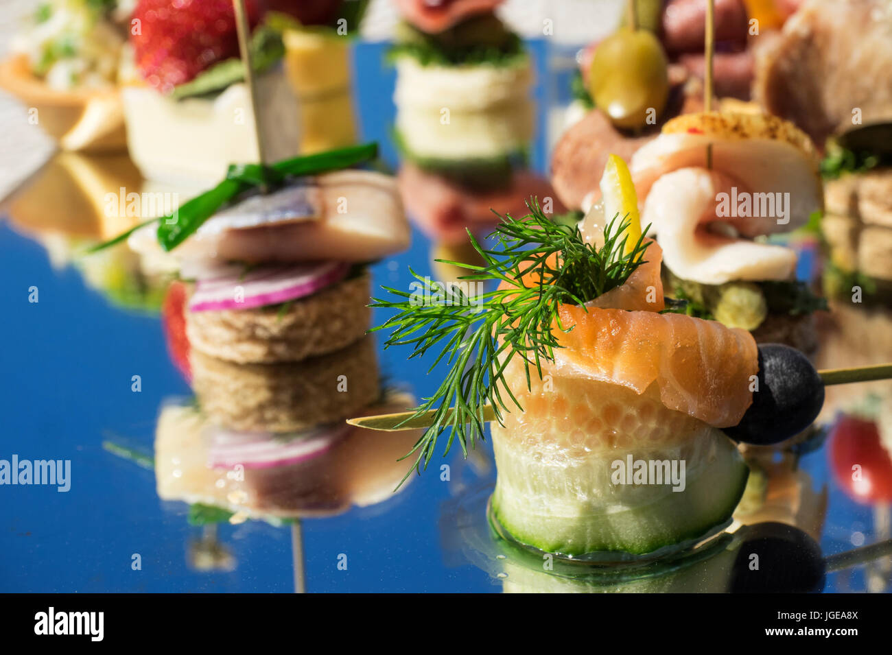 Set of different canapes and snacks served on a platter with a mirror ...