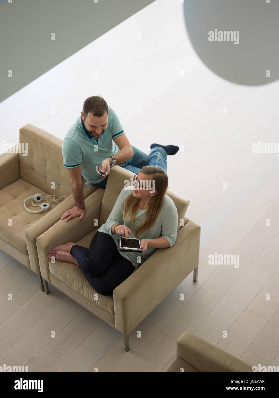 Young couple relaxing at luxurious home with tablet computers reading ...
