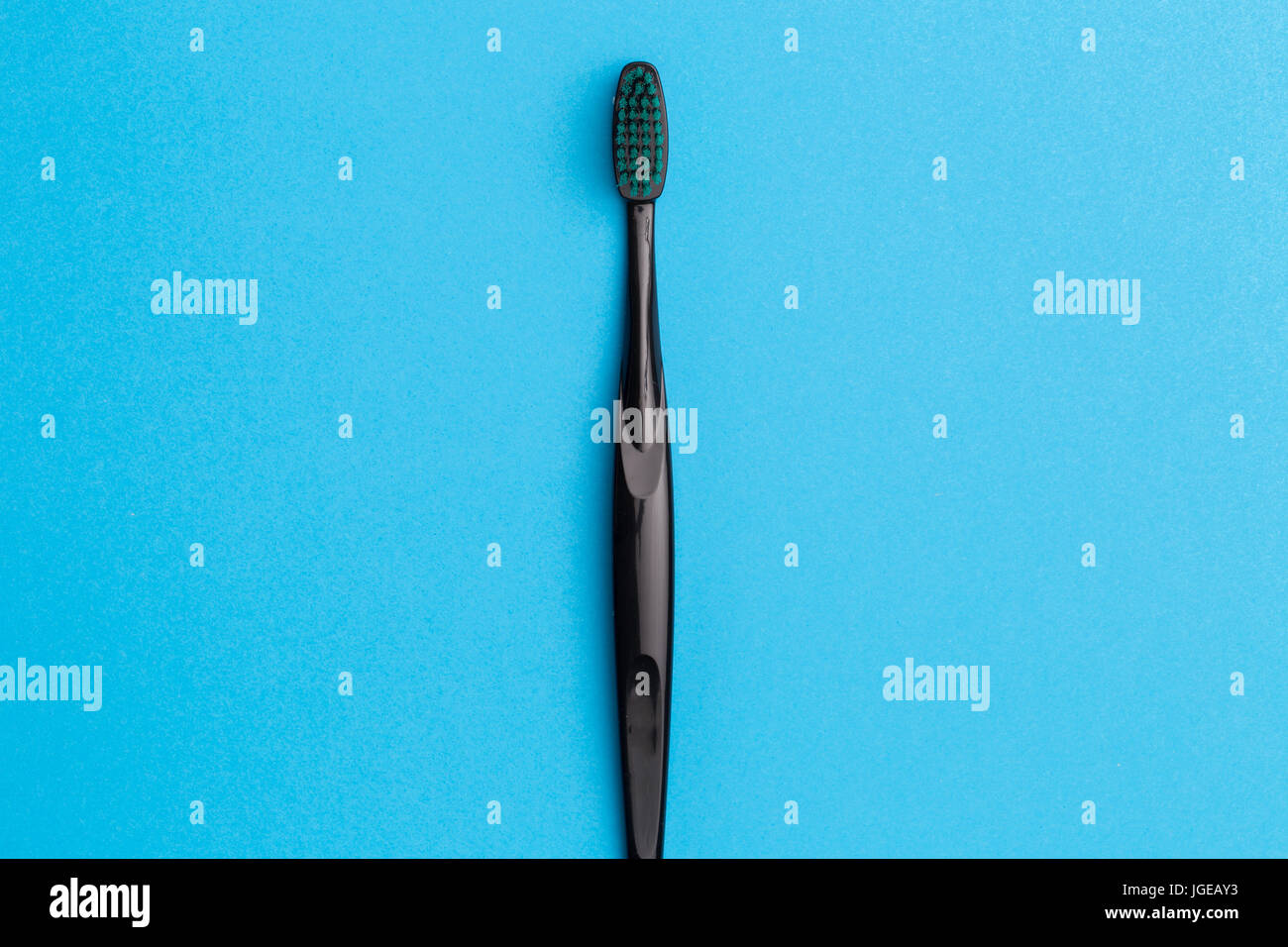 Image of one black toothbrush on empty blue background Stock Photo - Alamy