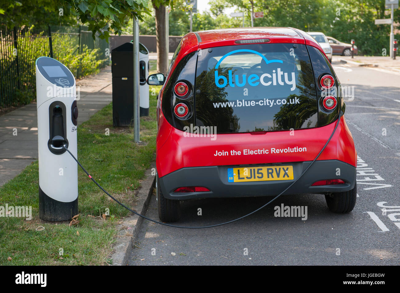 Electric city car recharging at charge point on London suburban street ...