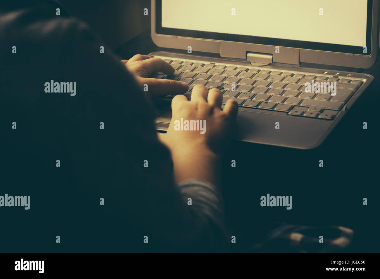 Kid using laptop in dark room Stock Photo - Alamy