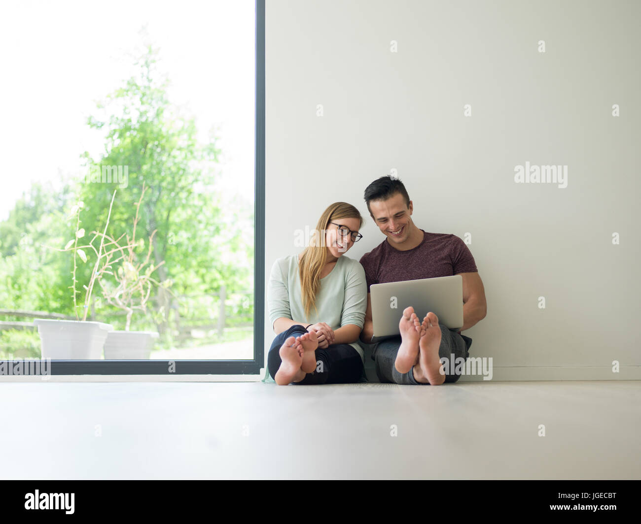 Young couple using laptop computer on the floor at luxury home together ...