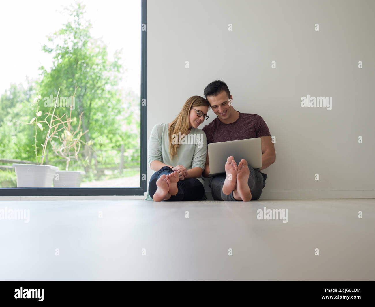 Young couple using laptop computer on the floor at luxury home together ...