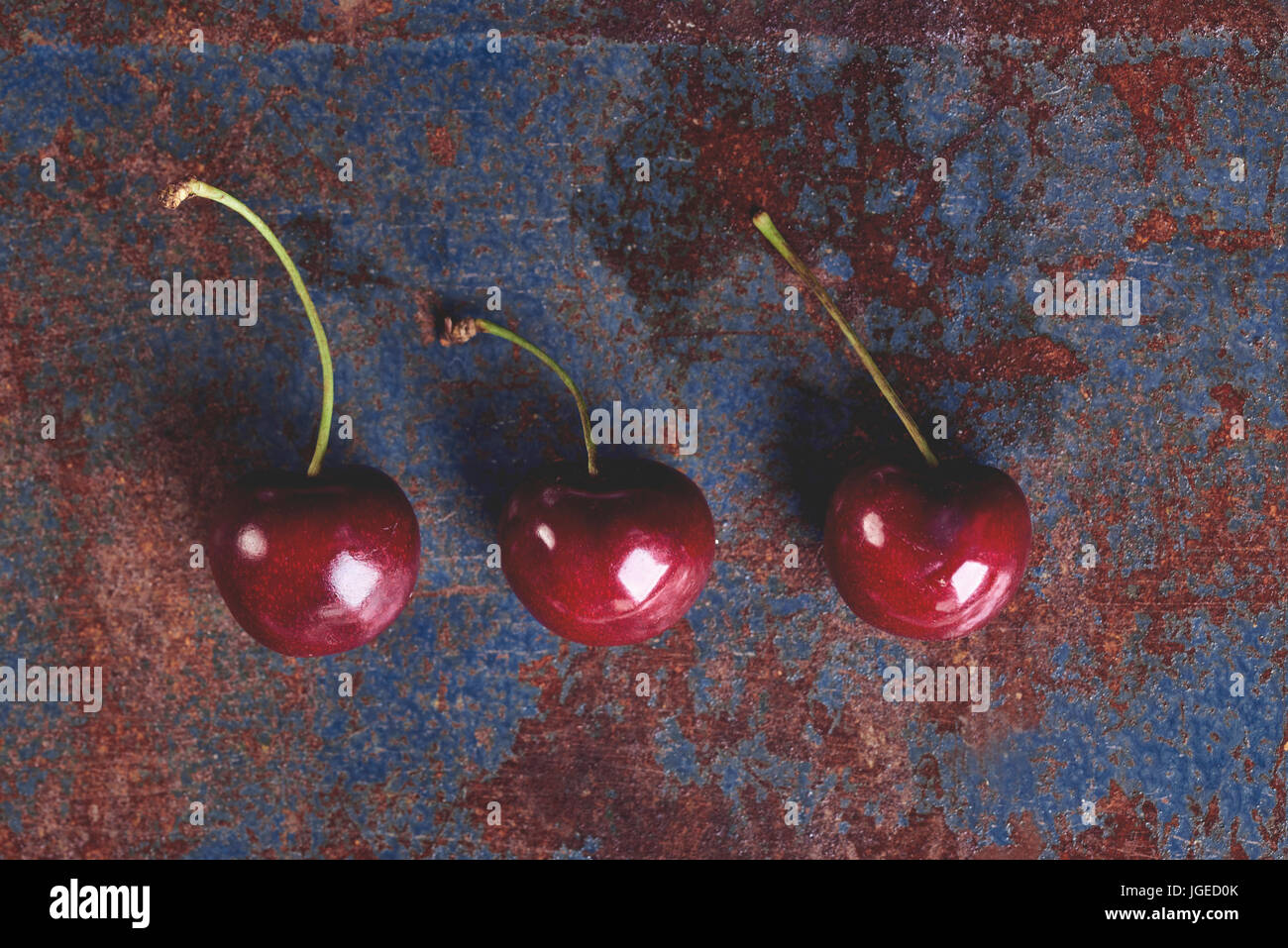 Three ripe cherry on the old table Stock Photo - Alamy