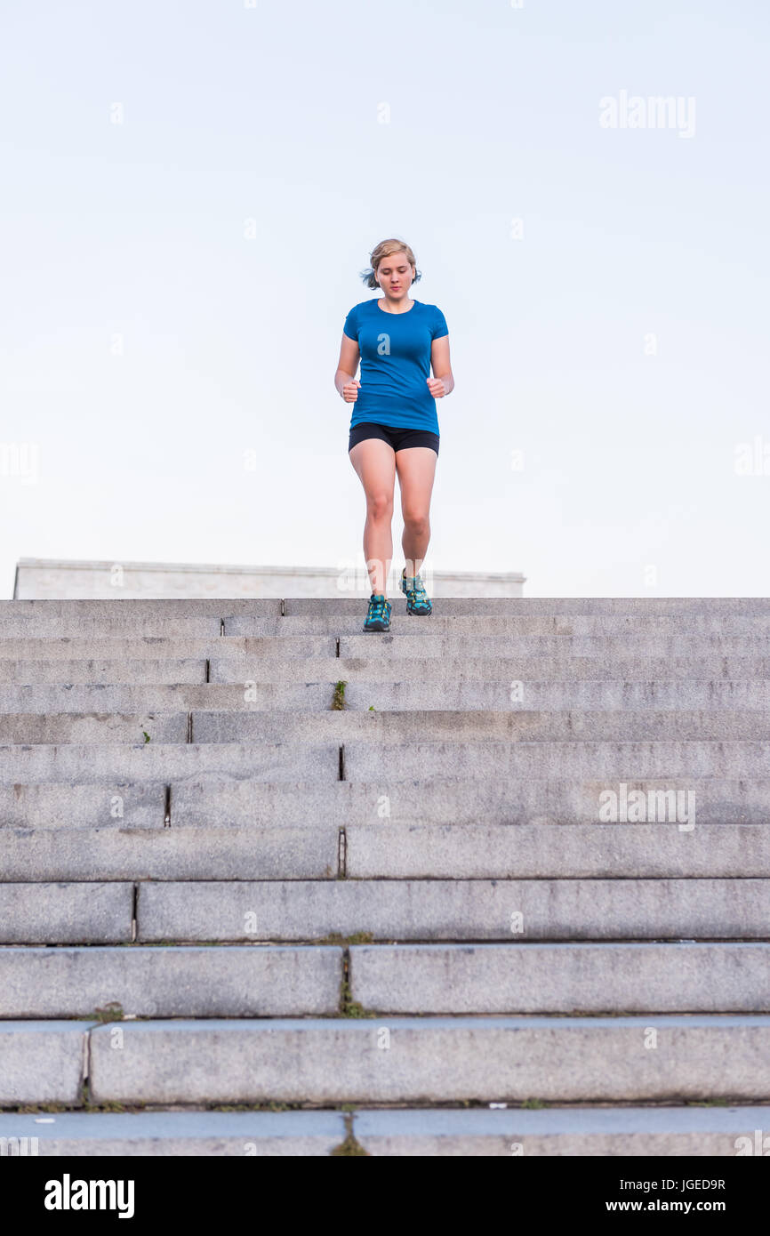Young fit woman running down steps outside during workout Stock Photo ...