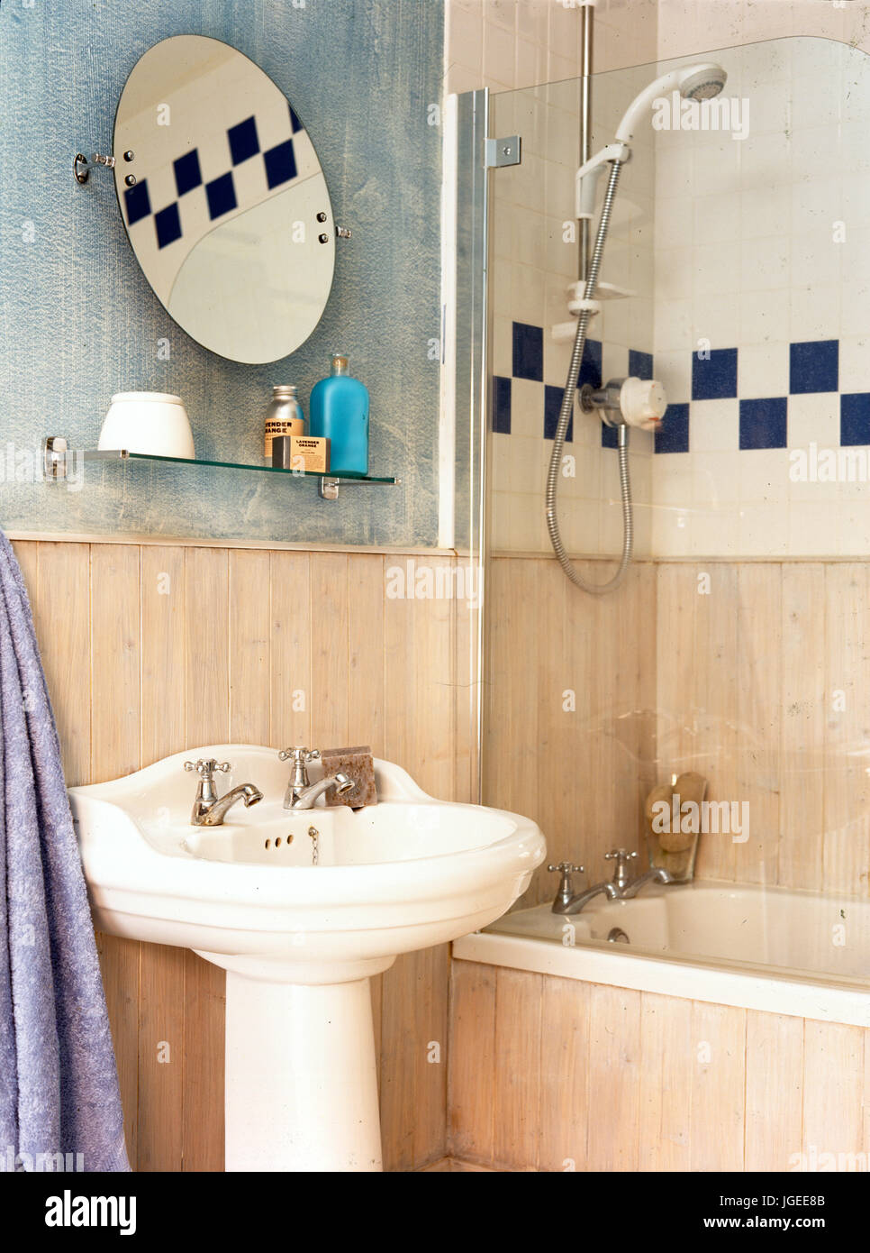 Shower above bath in bathroom with basin and circular mirror Stock ...
