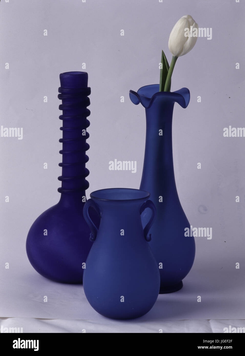 Three blue glass vases arranged with one white tulip Stock Photo - Alamy