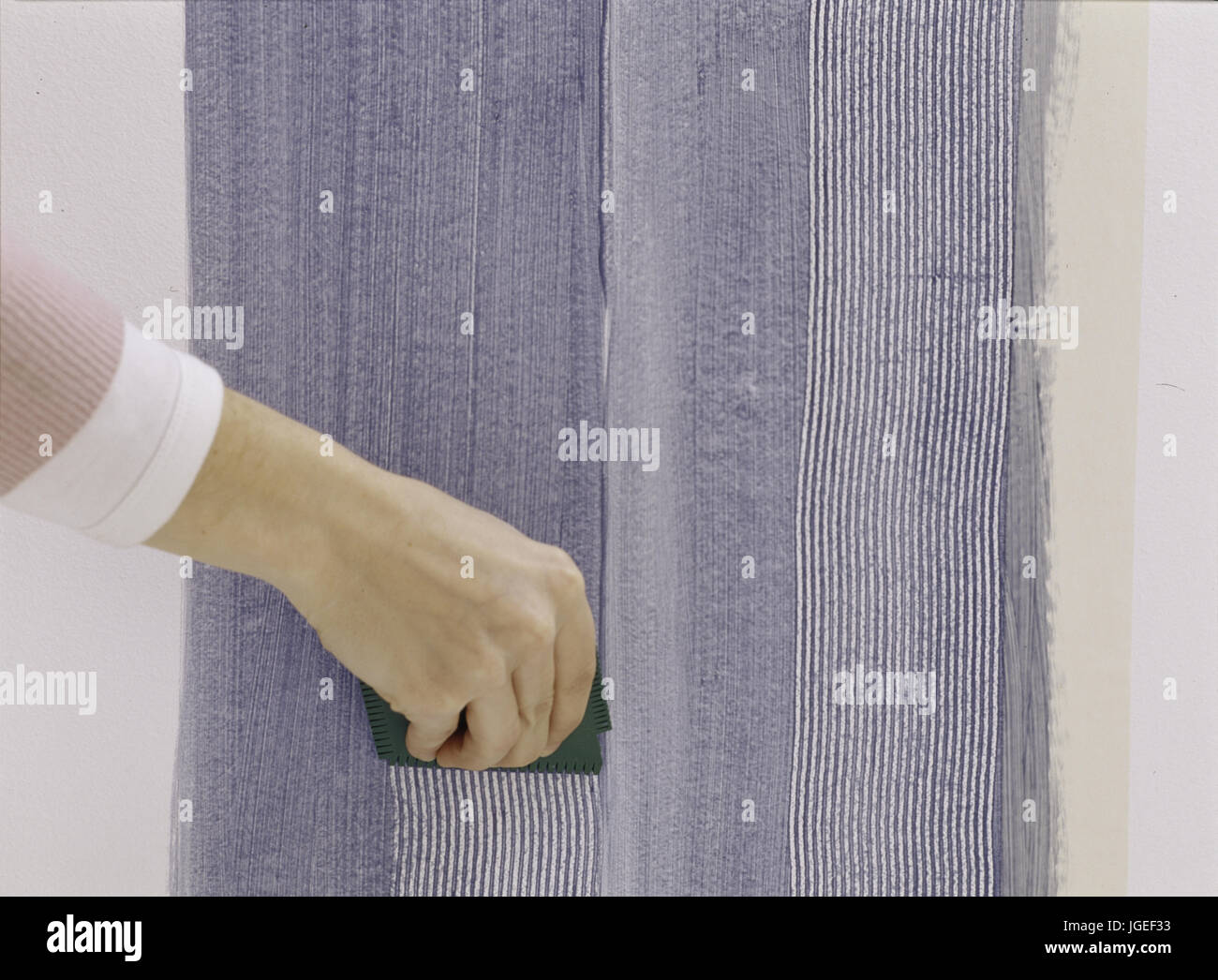 Close-up of hand creating a combing paint effect. *** Local Caption ...