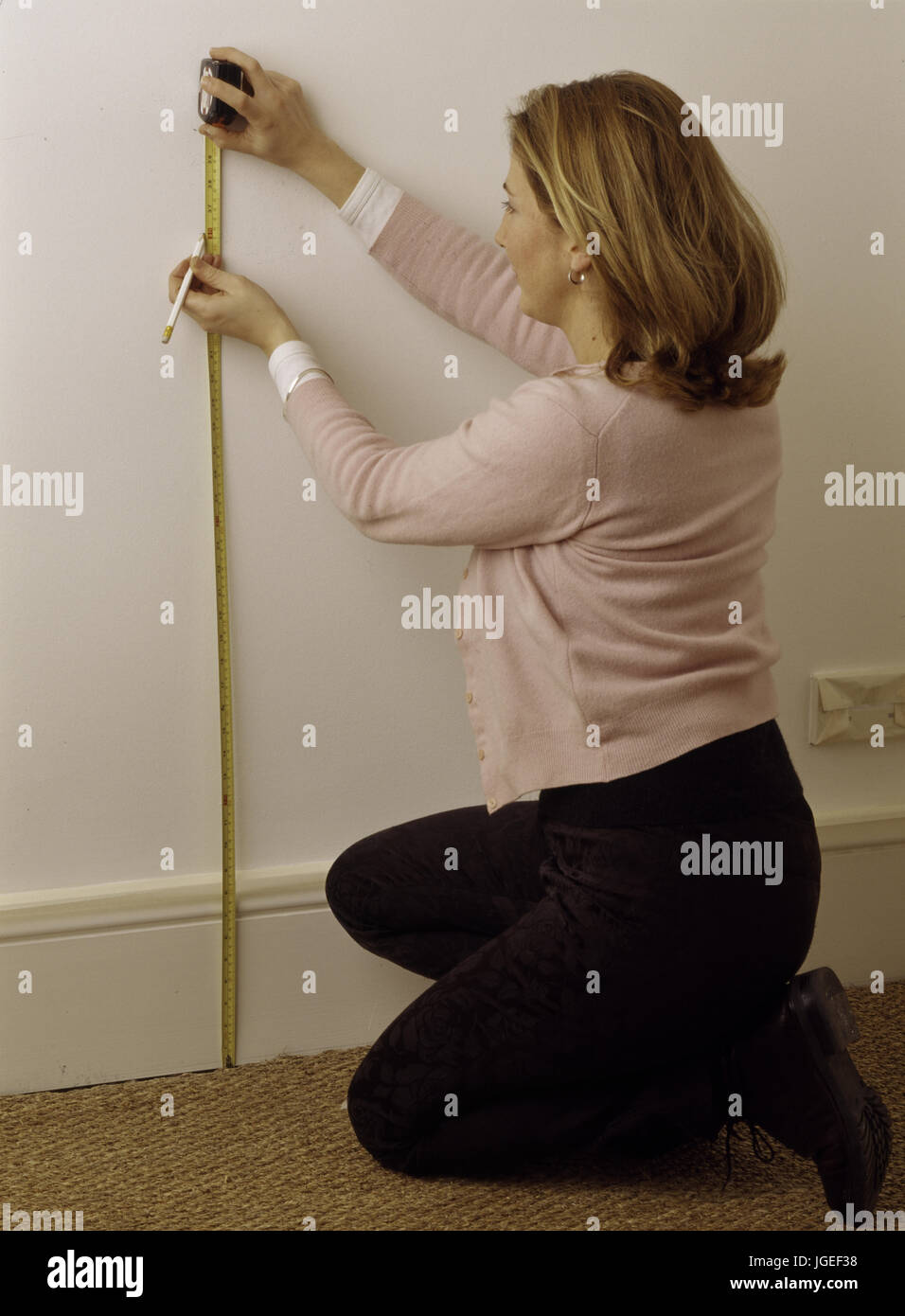 Woman measuring a wall. Step x step decorating. Step x step shots of ...