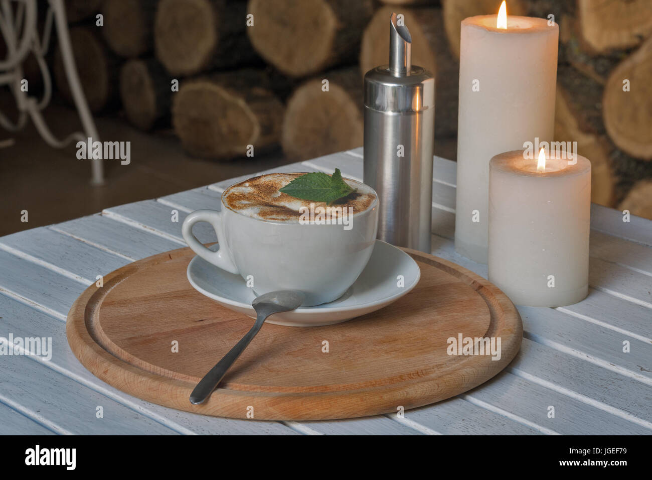 Coffee cup on bar table and romantic candles closeup with wooden logs ...
