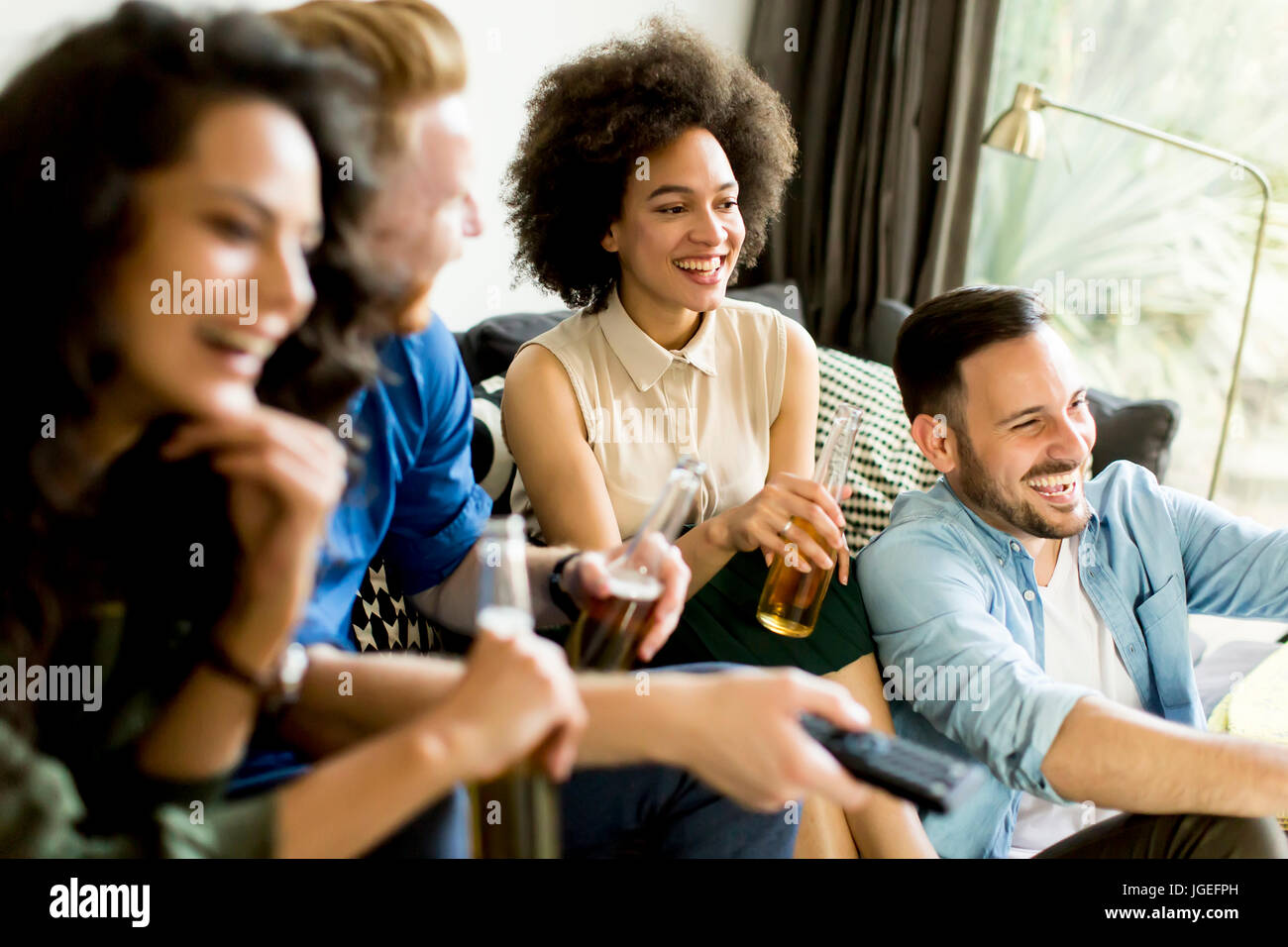 Group of friends watching TV , drinking cider and having fun in the ...