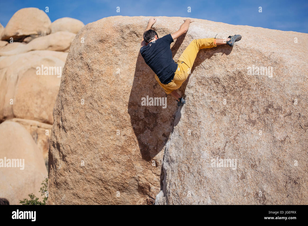 Young caucasian man rock climbs in the desert with no ropes or safety ...