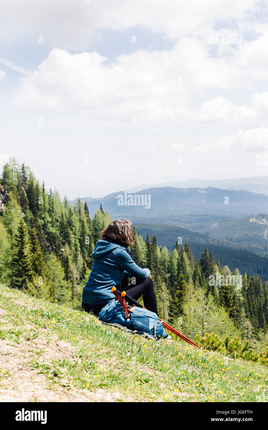 View at female hiker enjoying the mountain air sitting on a grass and ...